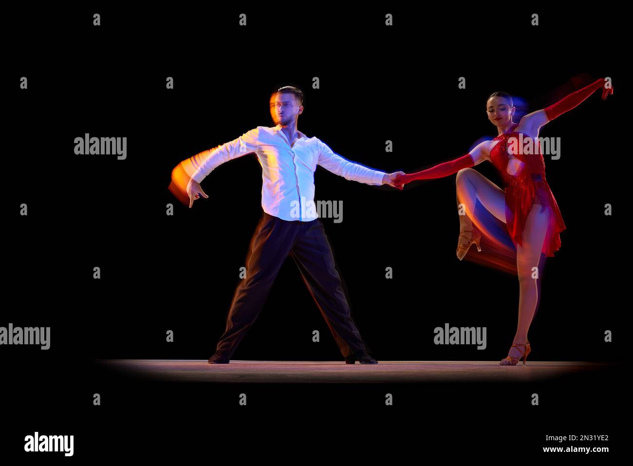 Man and woman, professional dancers in stylish stage costumes performing ballroom, tango over ...