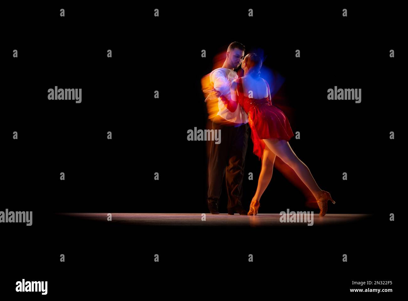 Man and woman, professional dancers in stylish stage costumes performing ballroom, tango over ...