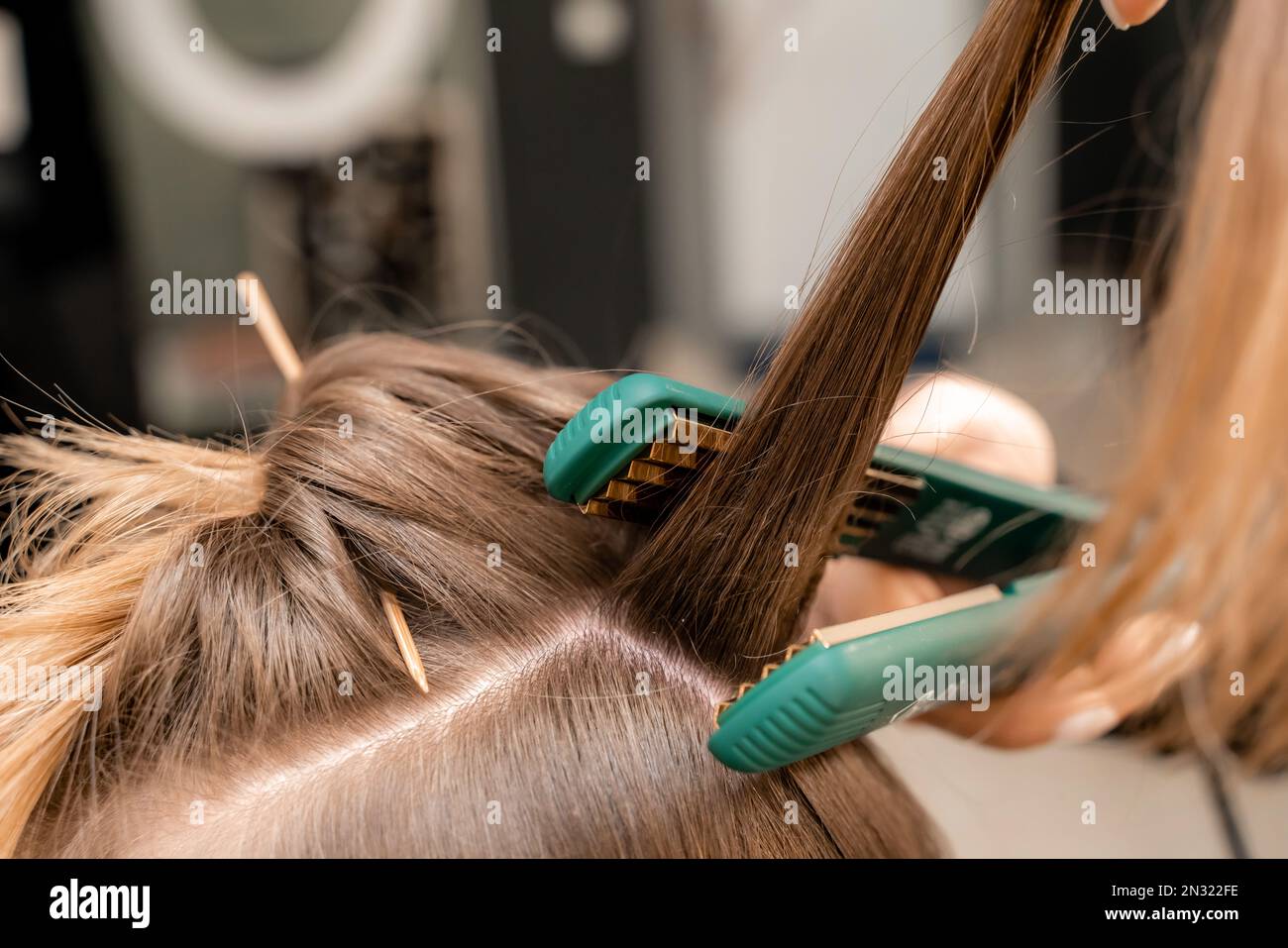 The hairdresser prepares a woman, makes a hairstyle with curls using a ...
