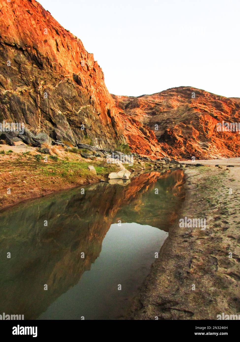 Reflections of the barren canyon cliffs in a pool in the Fish River of ...