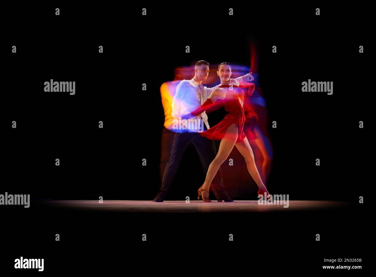 Expressive artistic young man and woman dancing tango, ballroom over black background with mixed ...