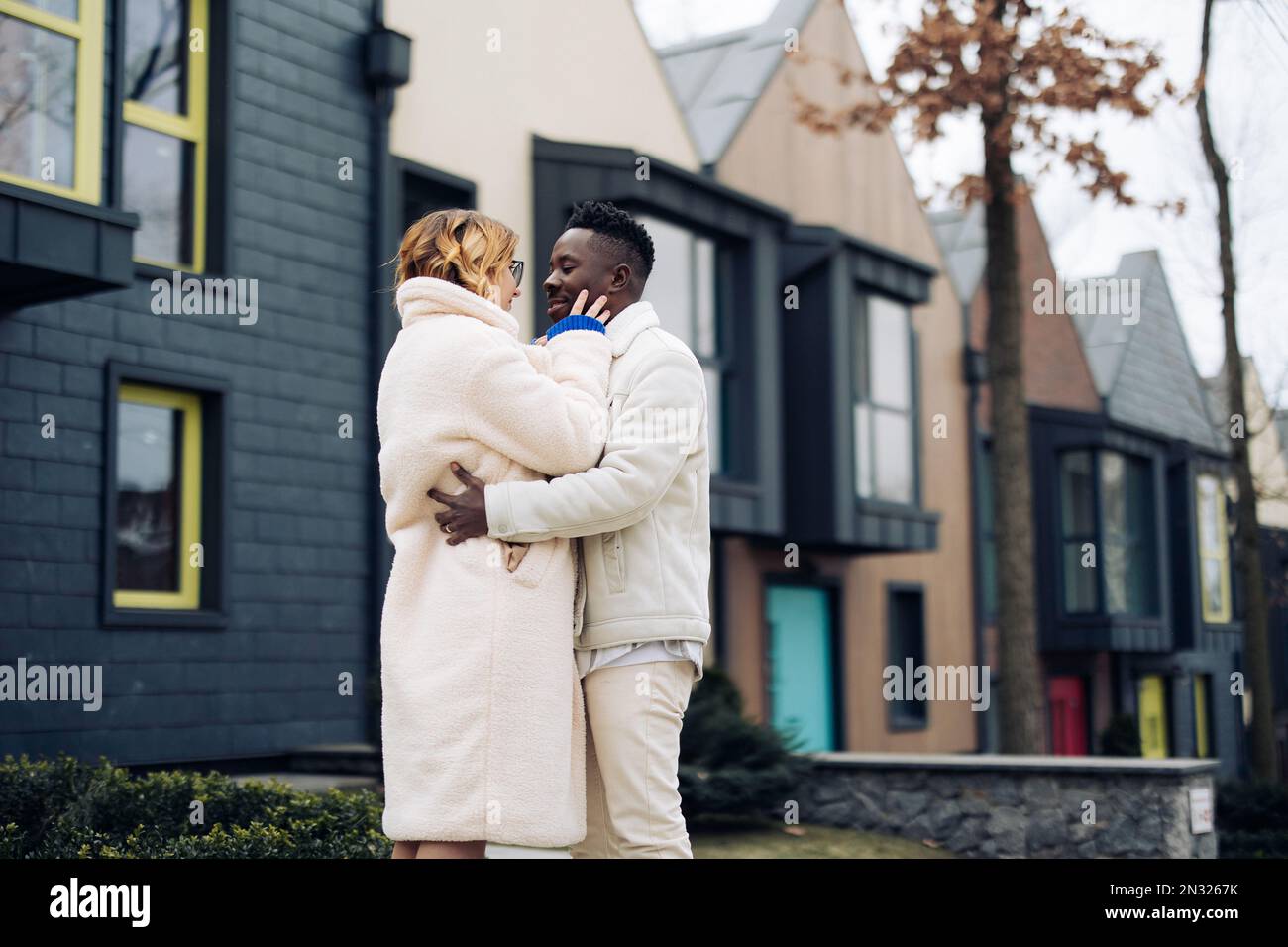 Young interracial couple embraces on street against background of ...