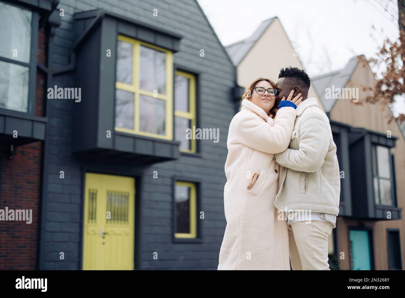 Young interracial couple embraces on street against background of ...