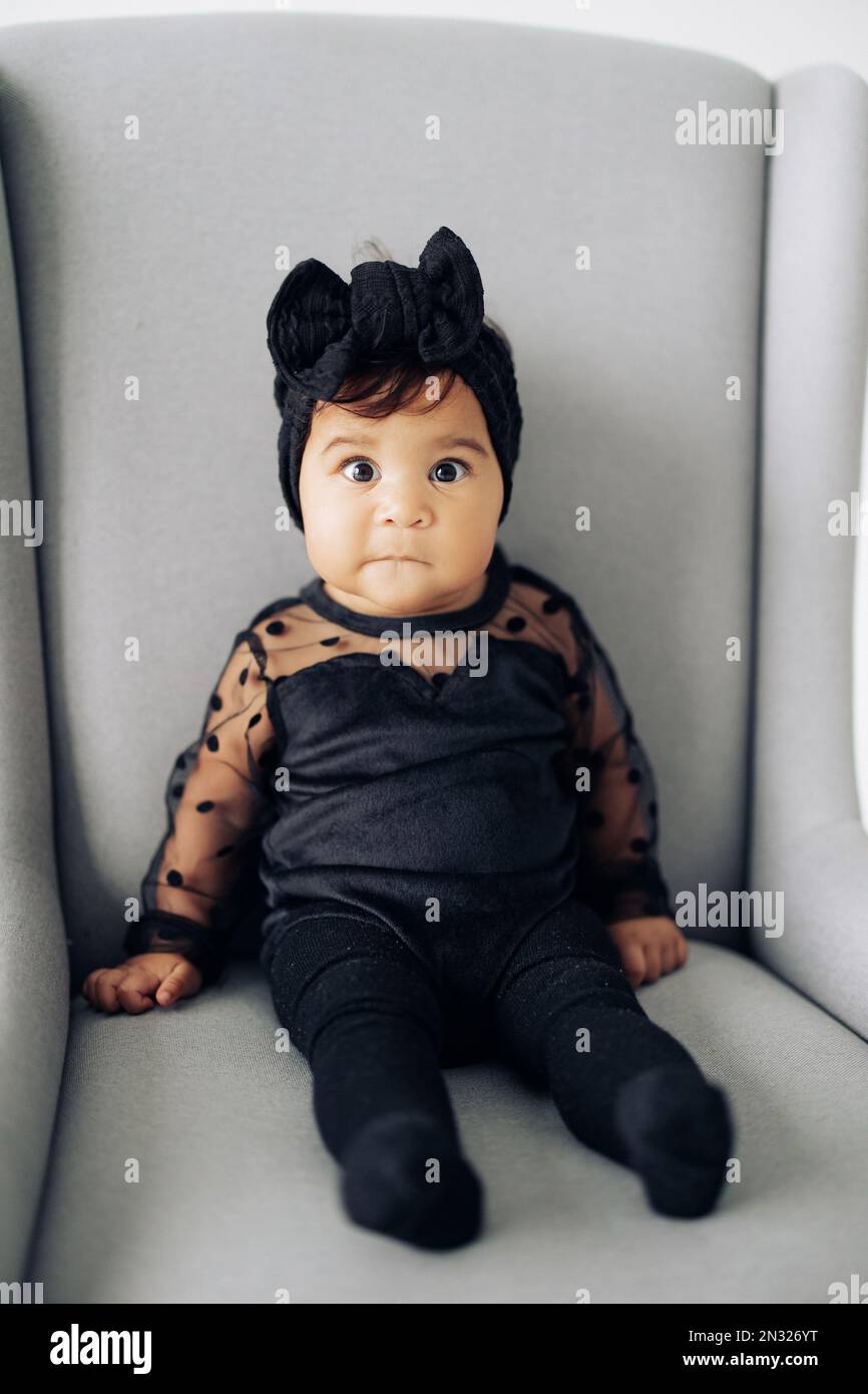 Happy baby girl from interracial marriage dressed in black dress with ...