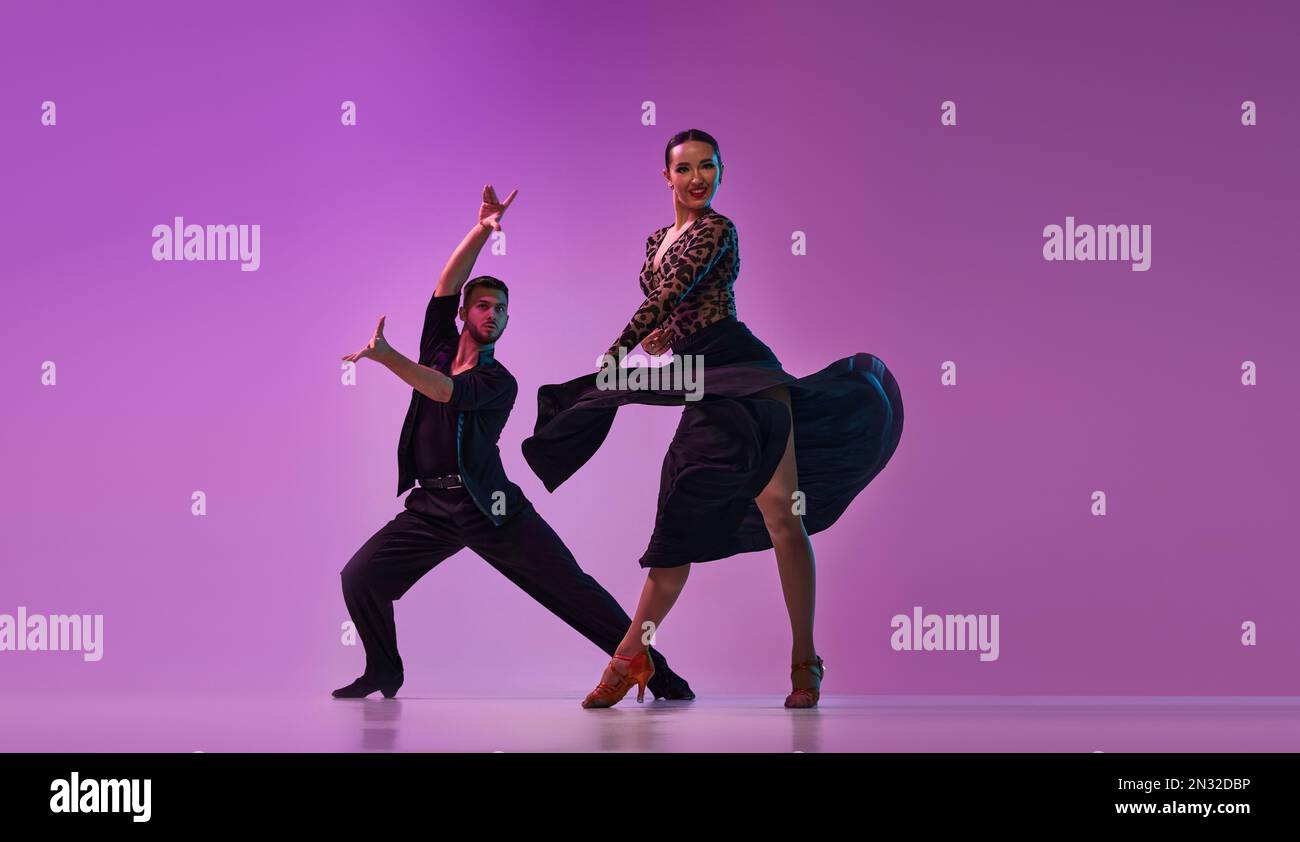 Artistic young man and woman, professional dancers in stylish stage costumes performing tango ...