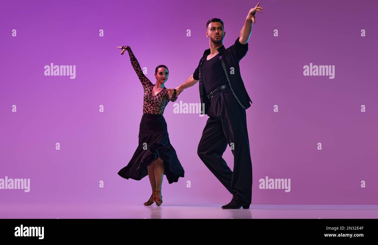 Young talented man and woman, professional dancers in stylish costumes performing tango over ...
