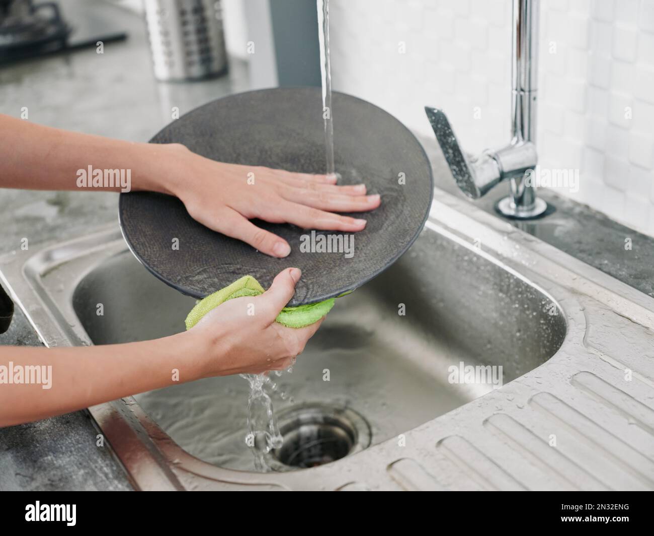 Woman with hands without gloves washes dishes with a dishwashing sponge ...