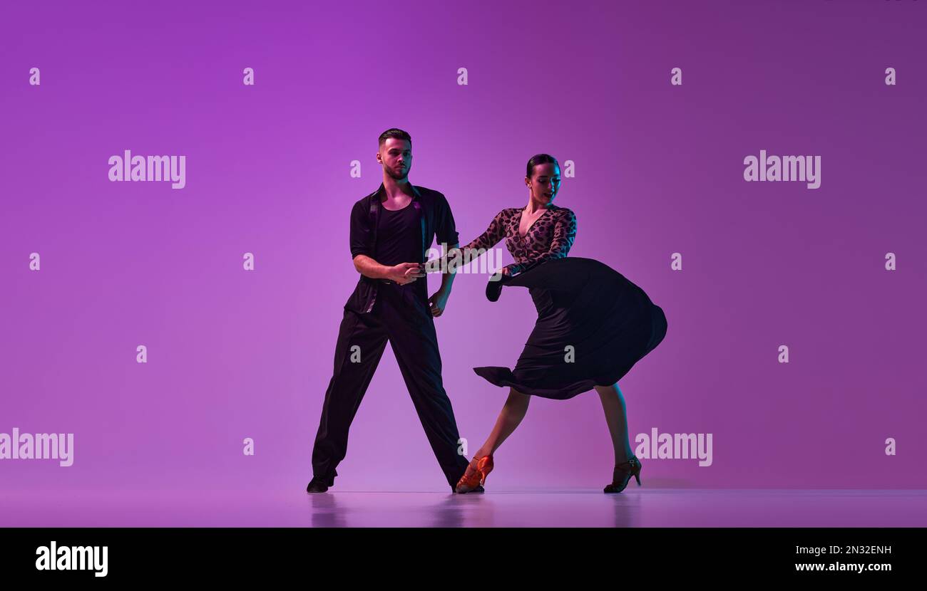 Artistic young man and woman, professional dancers in stylish stage costumes performing tango ...