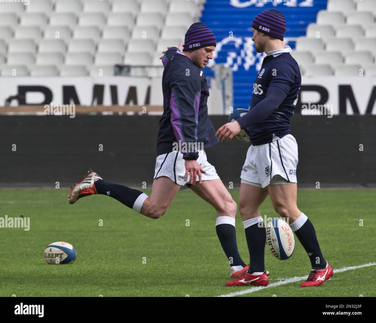 Scottish rugby players Finn Russell, left, kicks the ball past Peter ...