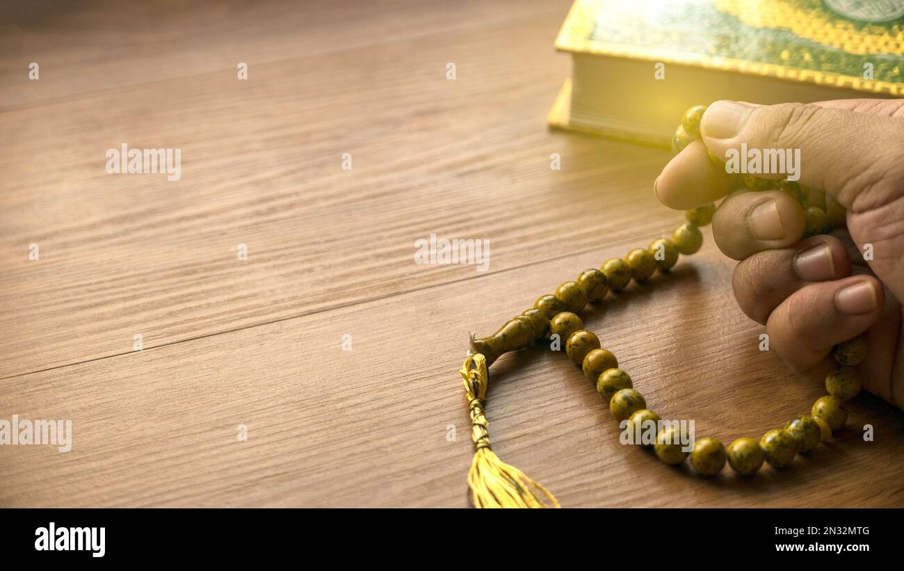 Selective focus of hand counting rosary beads with Quran on wooden ...
