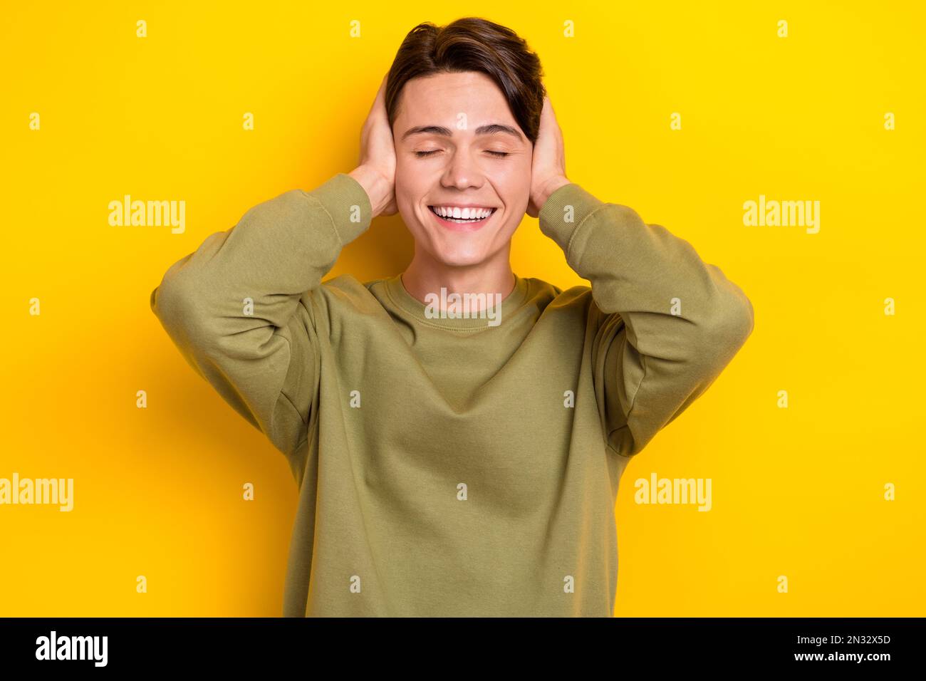 Photo of cheerful positive man wear khaki clothes arm cover ears loud ...