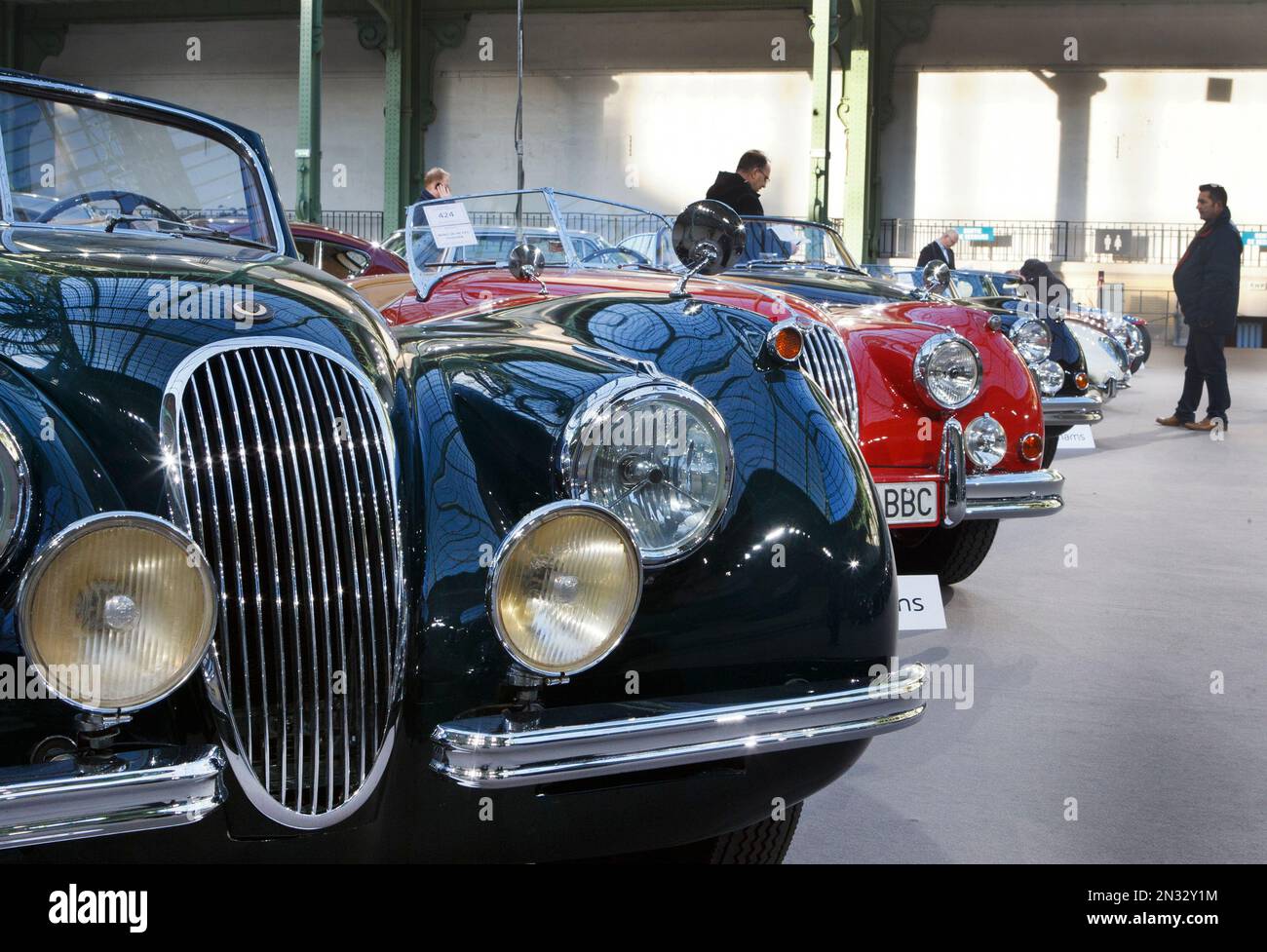 Visitors walk past vintage and classic cars displayed by Bonhams ...