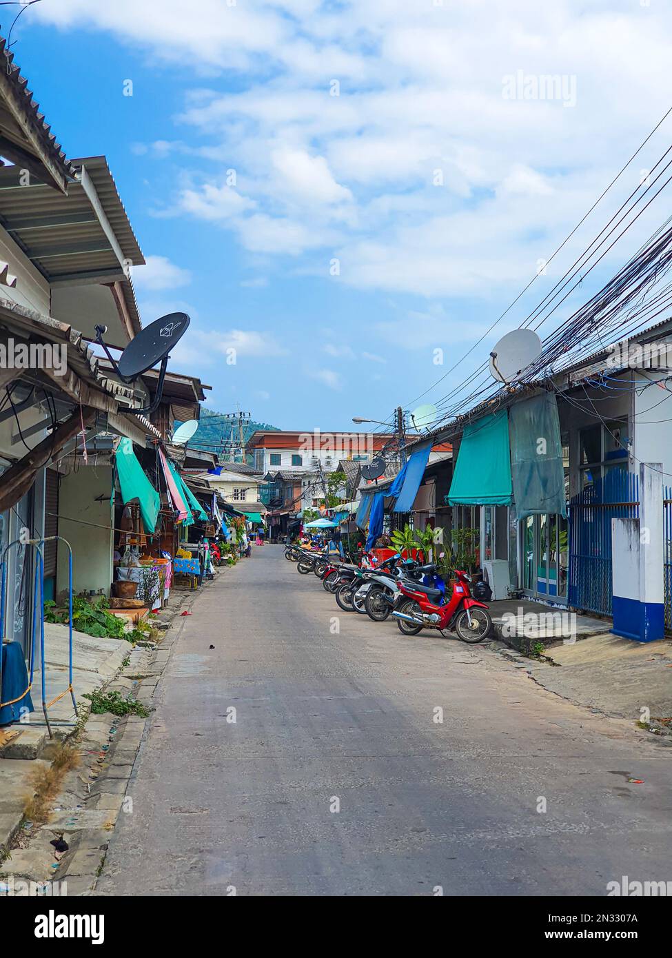 A vertical shot of local shops along a street with arrayed motorcycles ...