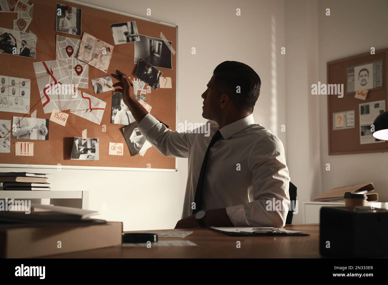 Detective looking at evidence board in office Stock Photo - Alamy
