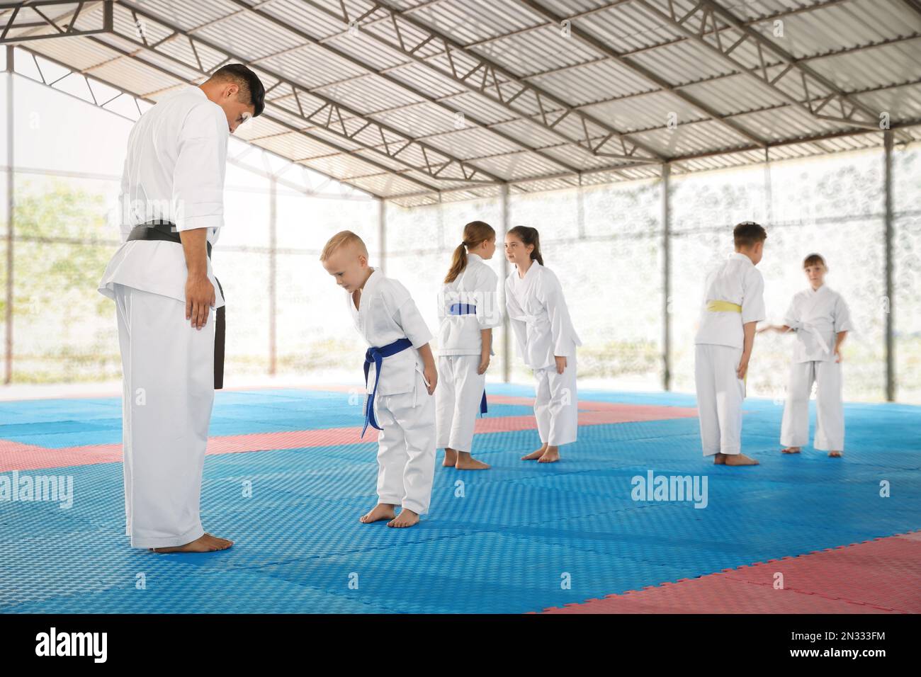 Children and coach in kimono performing ritual bow before karate ...