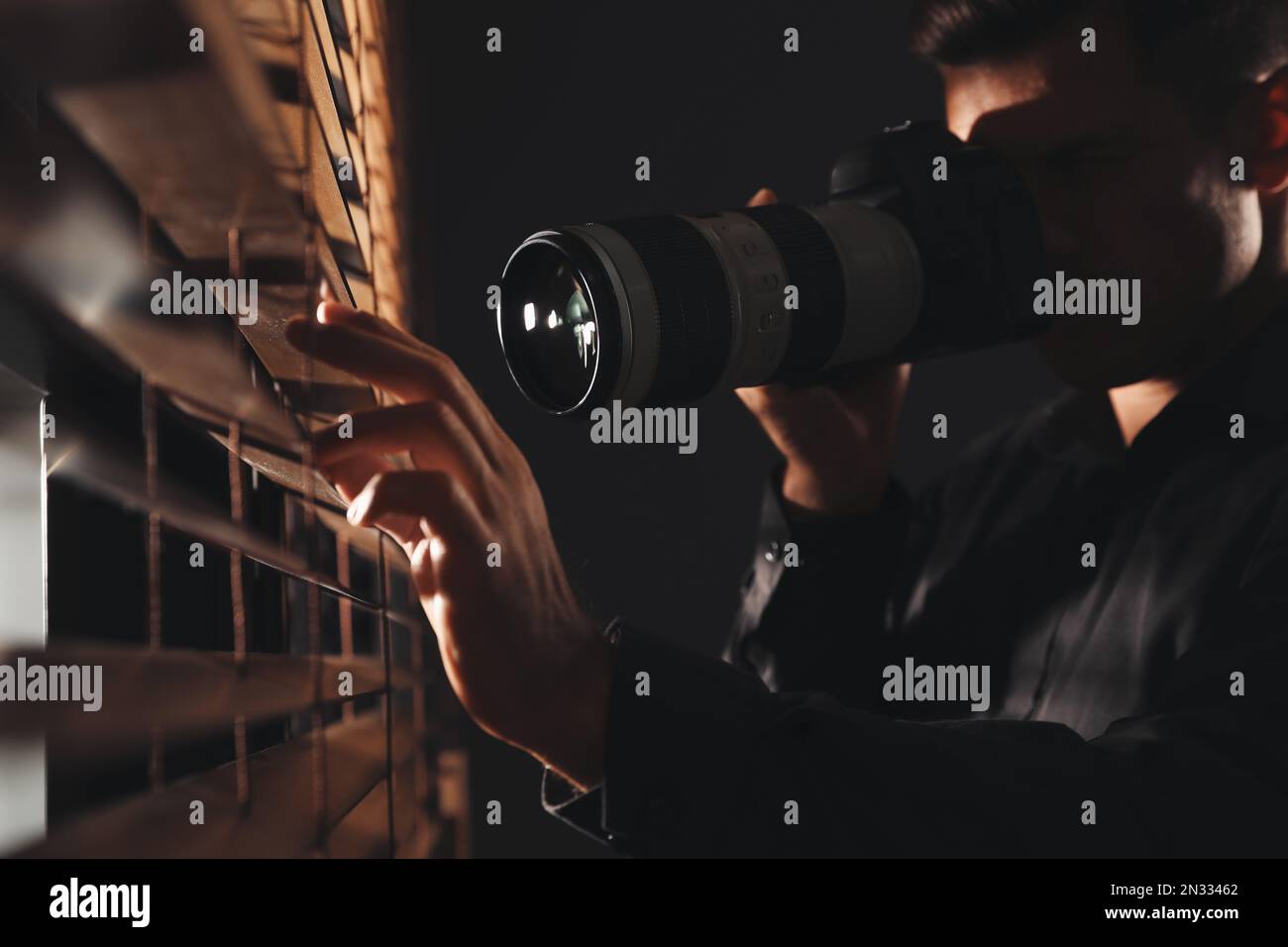 Private detective with camera spying near window indoors Stock Photo ...