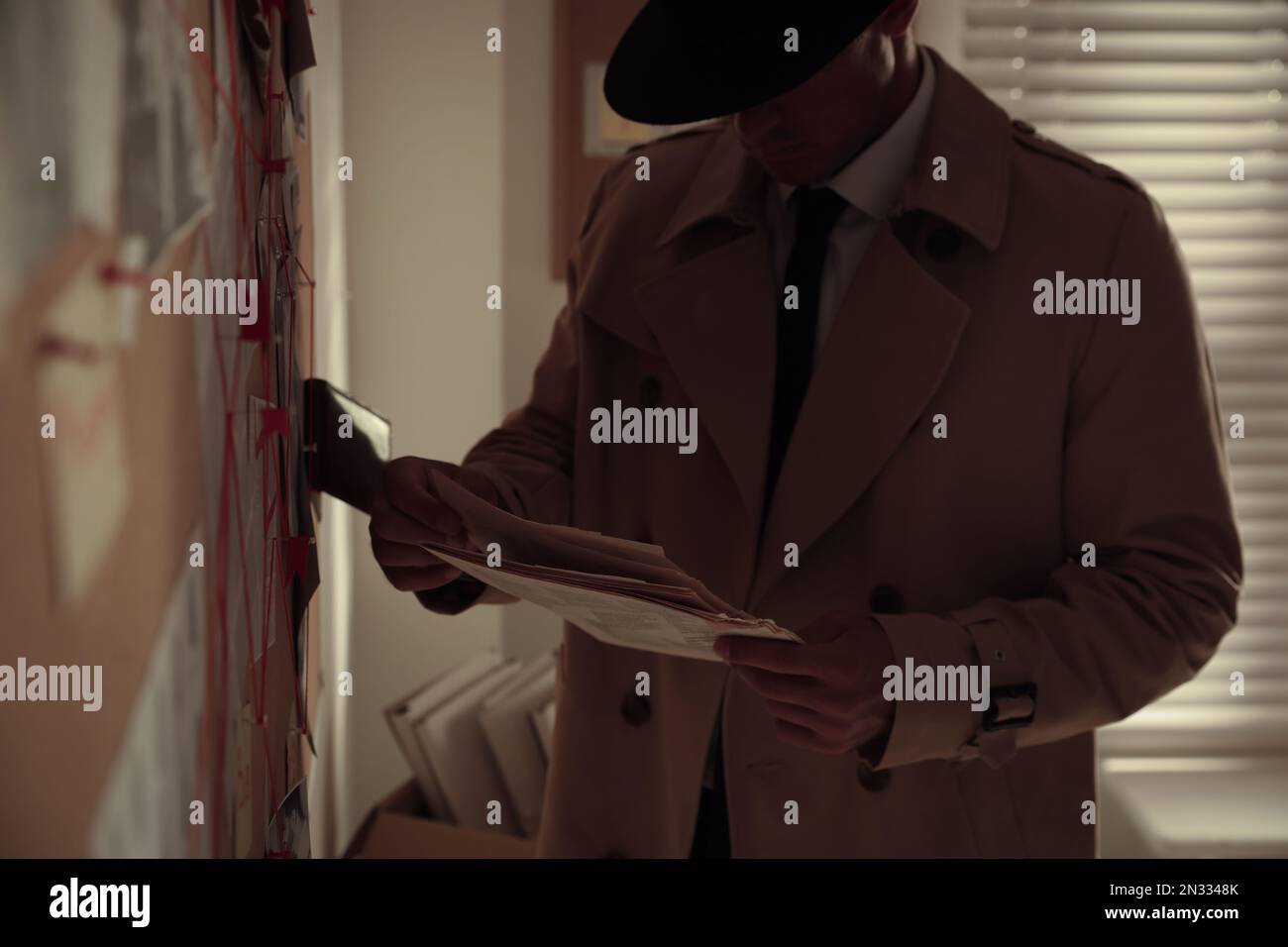Detective with newspaper near evidence board in office, closeup Stock ...