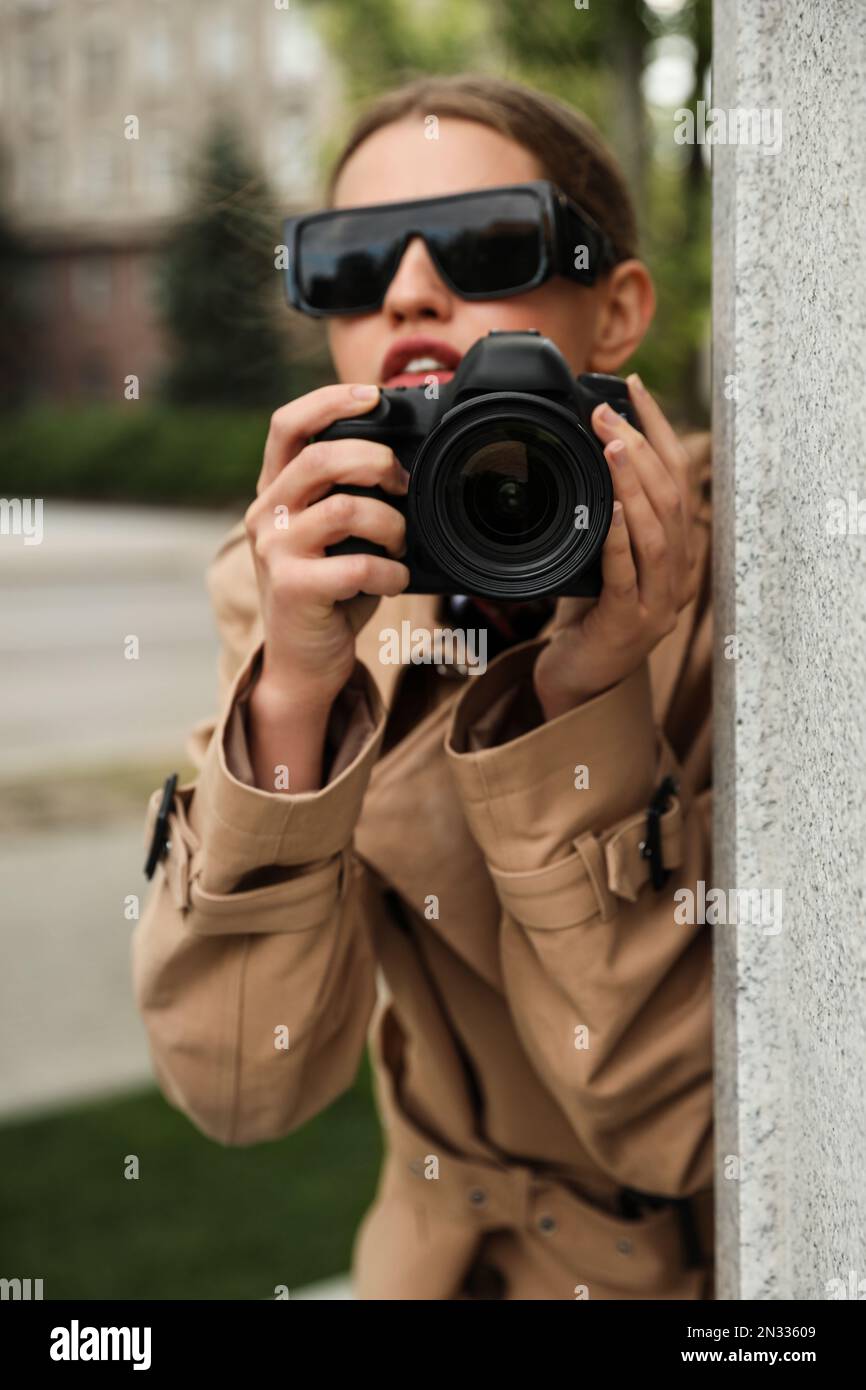 Private detective with modern camera spying outdoors, focus on lens ...