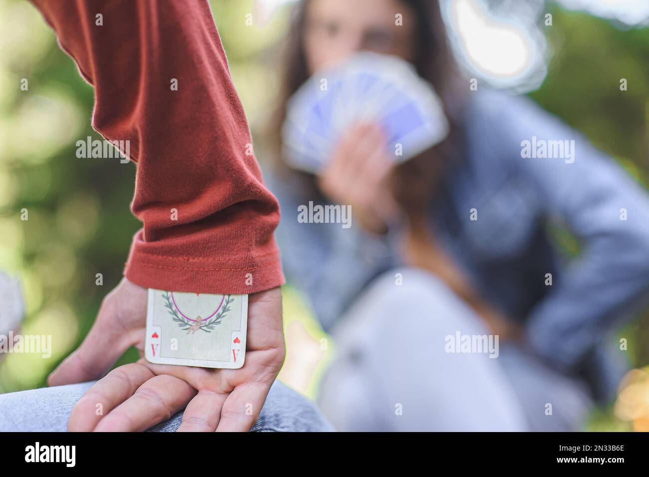 A young happy couple playing cards in a spring garden: the young man ...