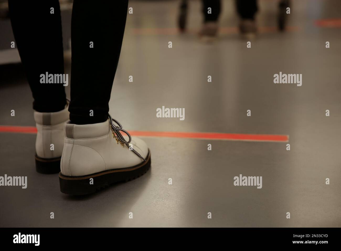 Woman standing behind taped floor marking indoors for social distance ...