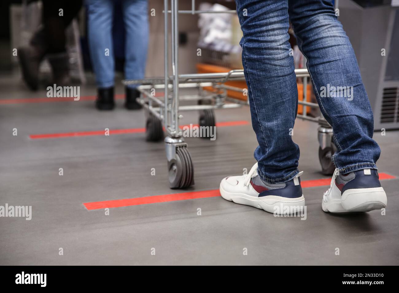 Person with shopping cart standing behind taped floor marking in store ...