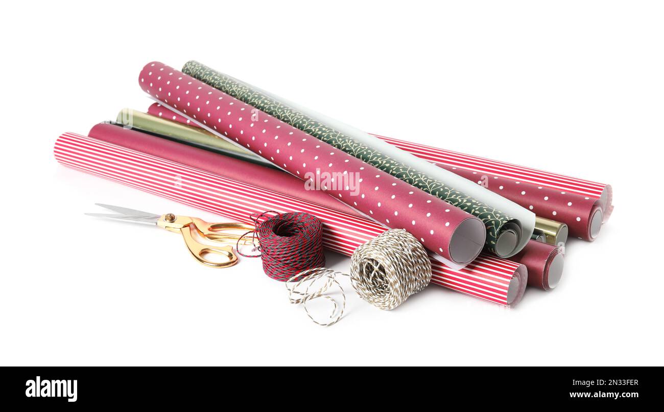 Different colorful wrapping paper rolls, scissors and ropes on white ...