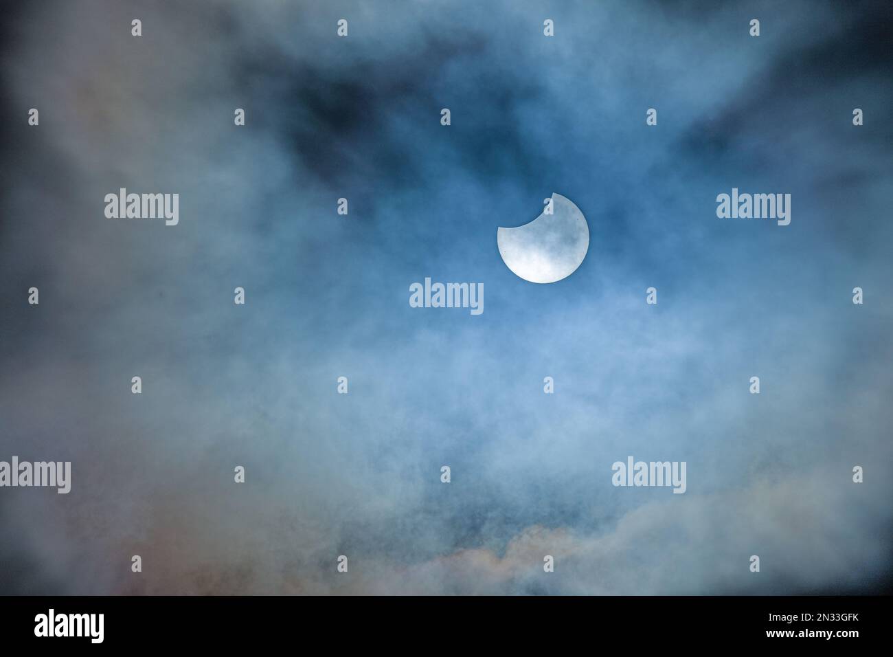 Image of a partial solar eclipse through veil clouds at noon time Stock Photo - Alamy