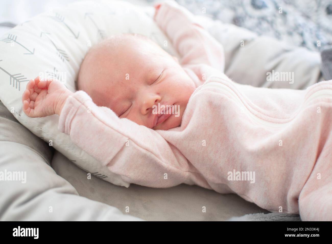 Cute caucasian baby stretching in her sleep. Sleeping newborn baby in a ...