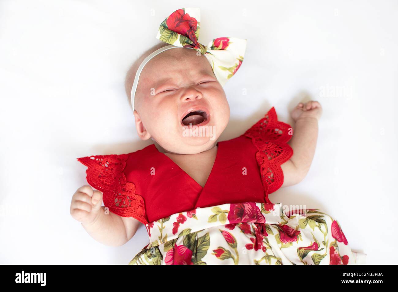 crying caucasian baby girl in a red dress. Crying child Stock Photo - Alamy