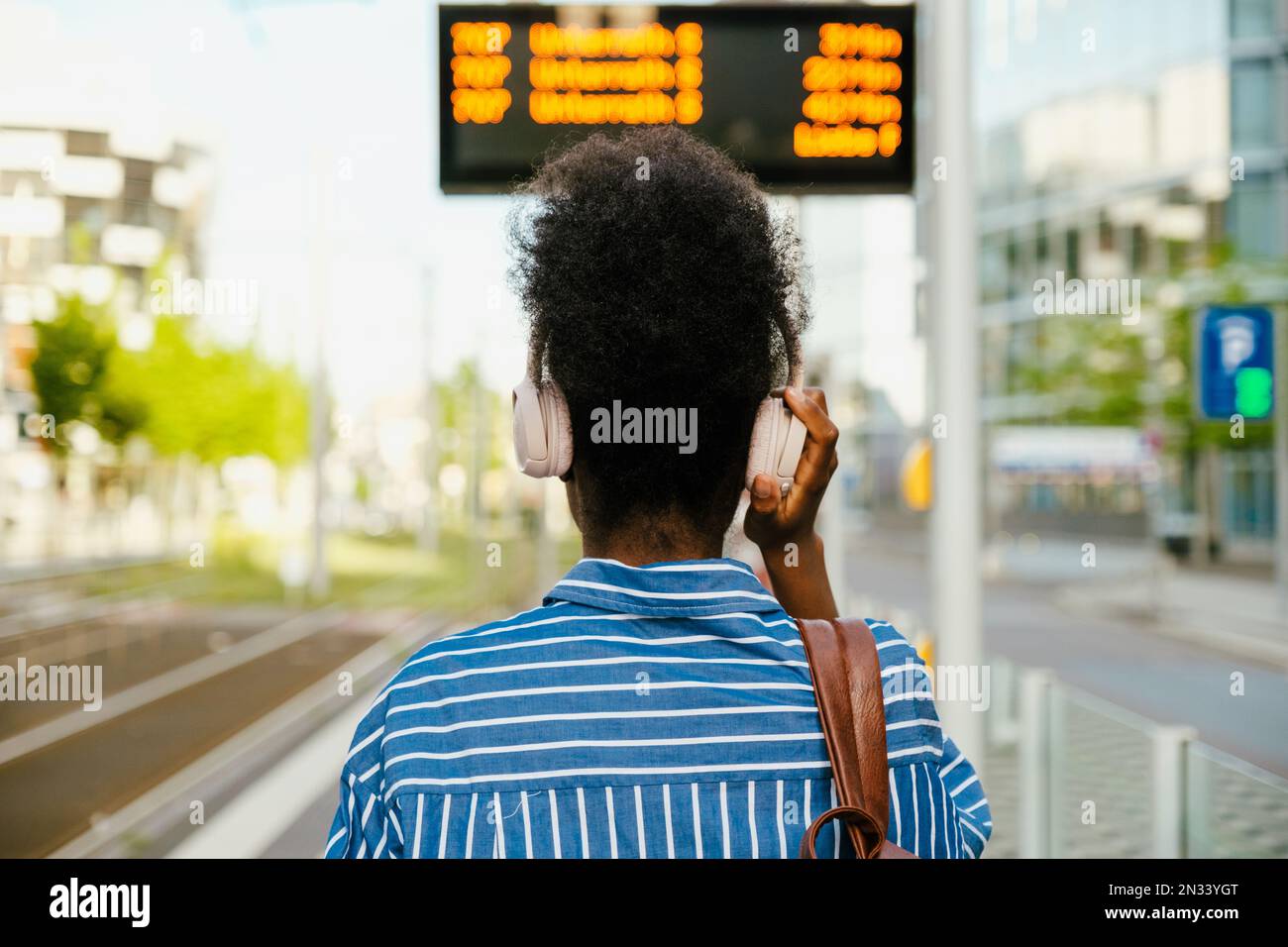 Portrait of african woman in headphones standing with her back with ...
