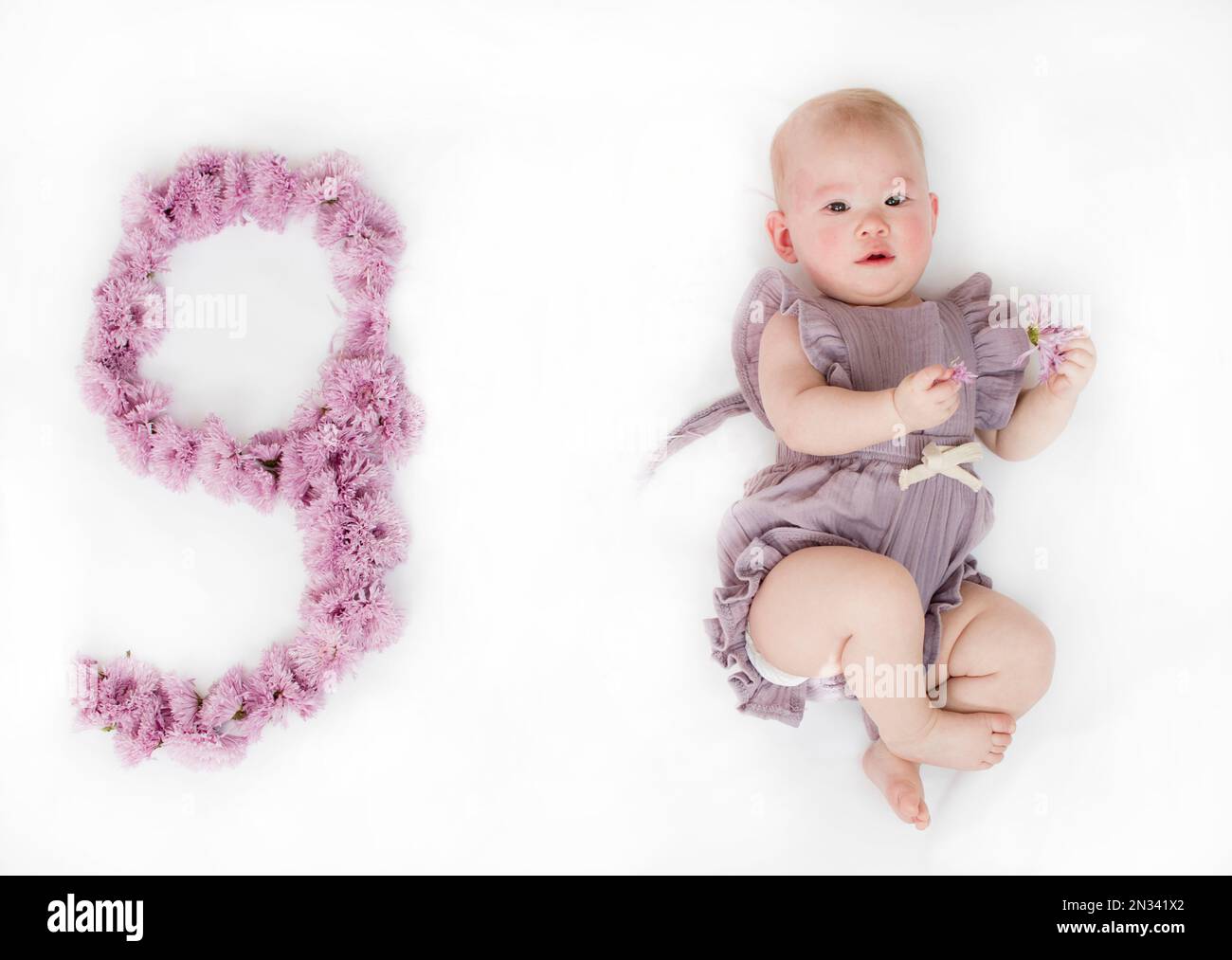 Little newborn baby girl in a purple romper. 9-month-old baby. Nine ...