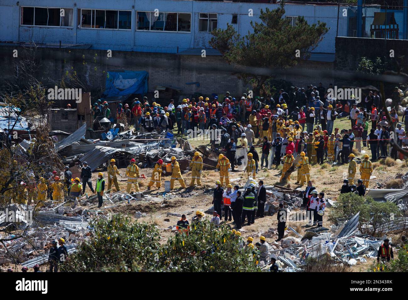 Rescue workers form a human chain, passing buckets of rubble, as they ...