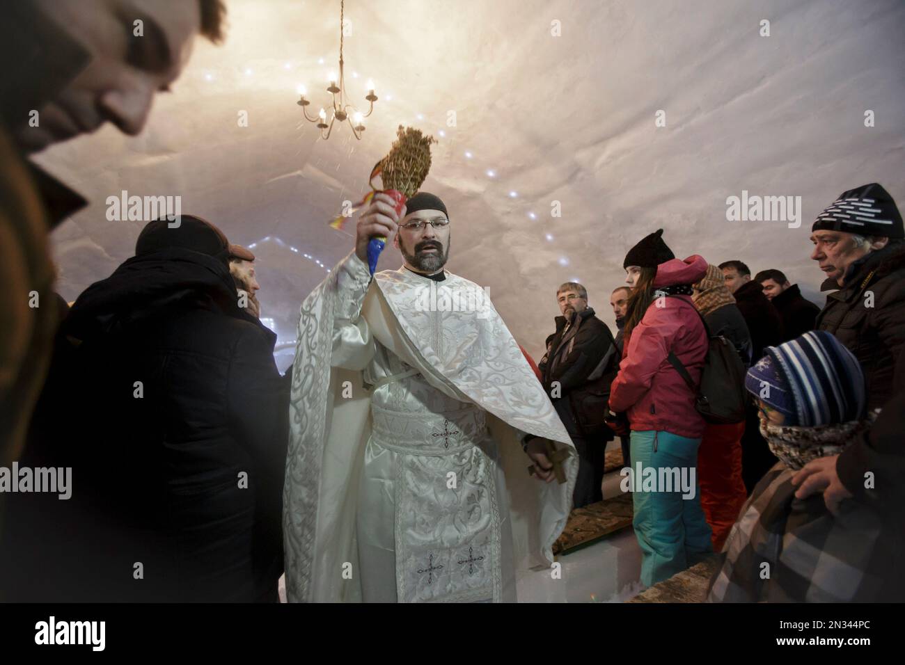 A Romanian priest sprinkles believers with holy water inside a church ...