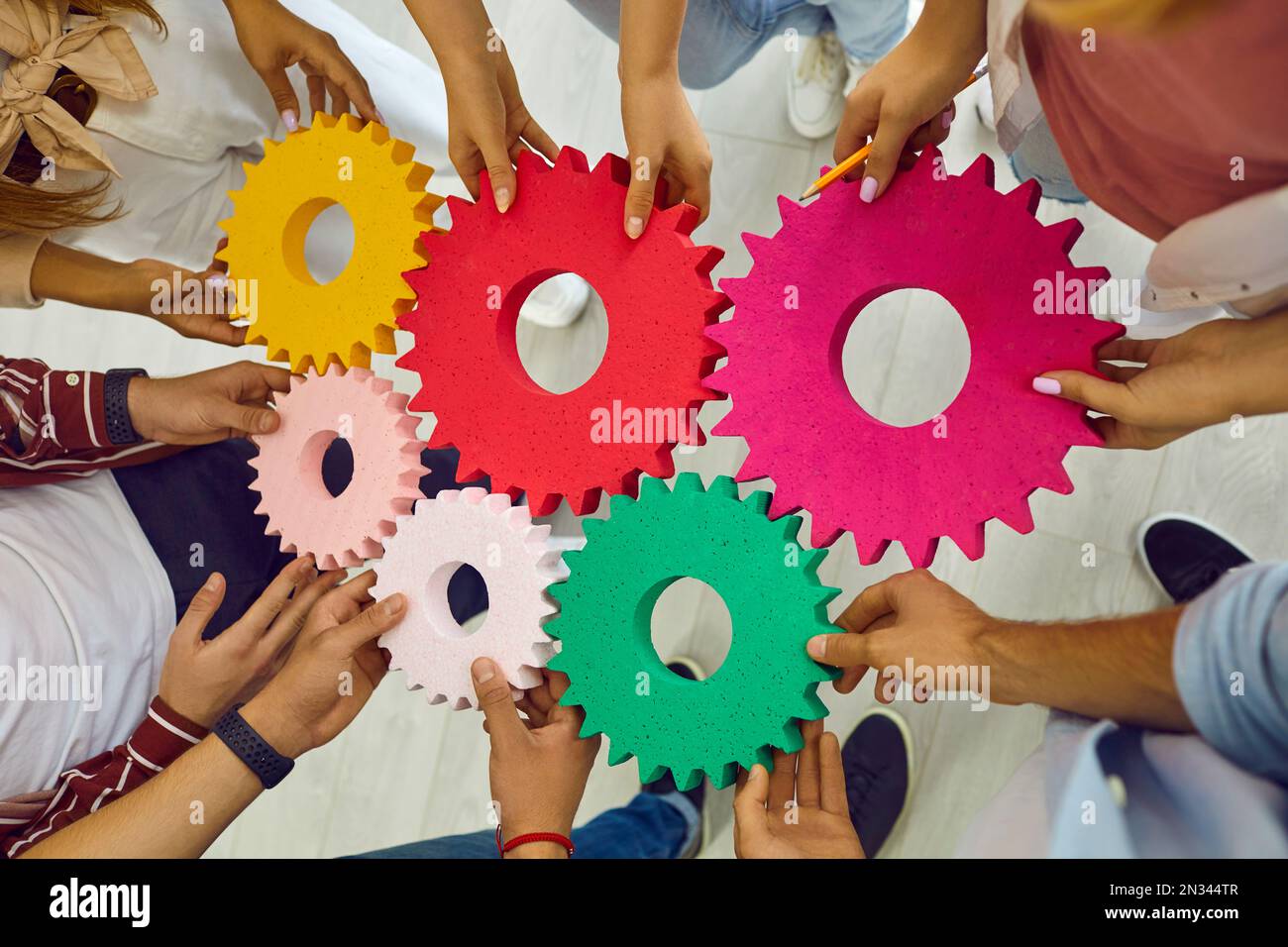 Team of people connecting colorful cogwheels to show concept of ...