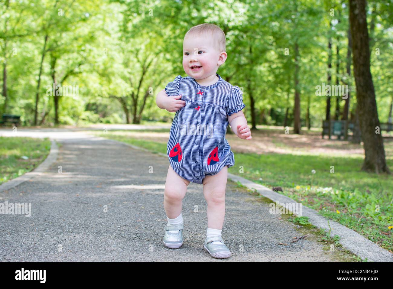 Cute caucasian baby taking first steps in the park. Toddler walking ...