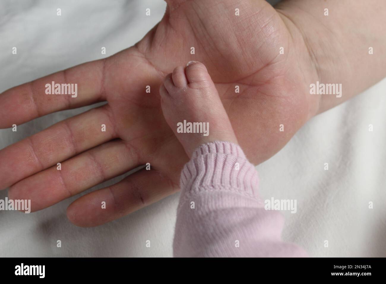 a small leg of a baby born on the arm of a man's father in close-up ...