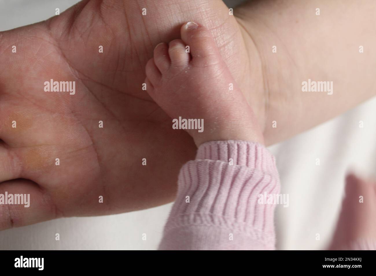 a small leg of a baby born on the arm of a man's father in close-up ...