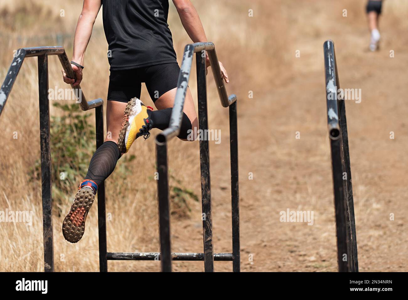 Participant in extreme obstacle race climbing over hurdle Stock Photo ...