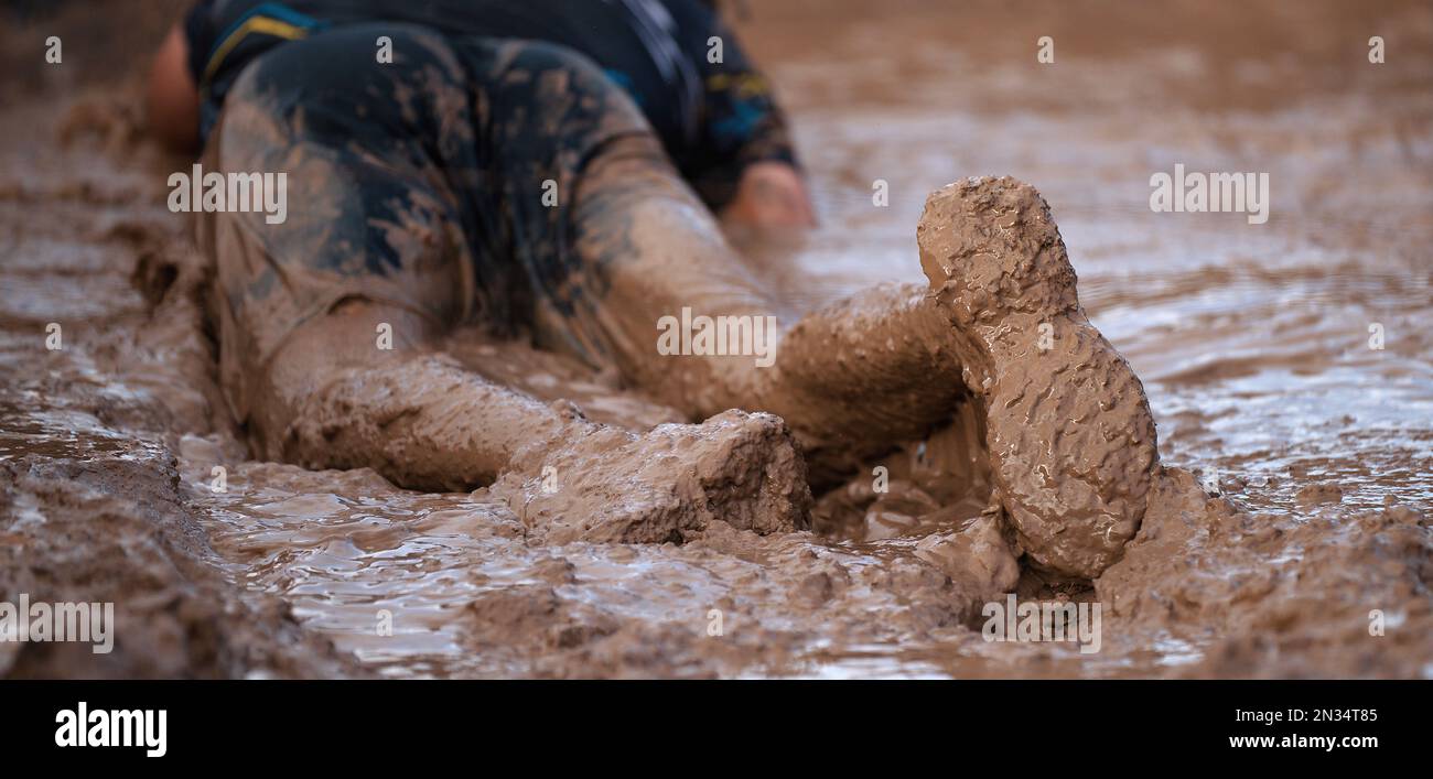 Mud race runners. Crawling, passing under a barbed wire obstacles ...
