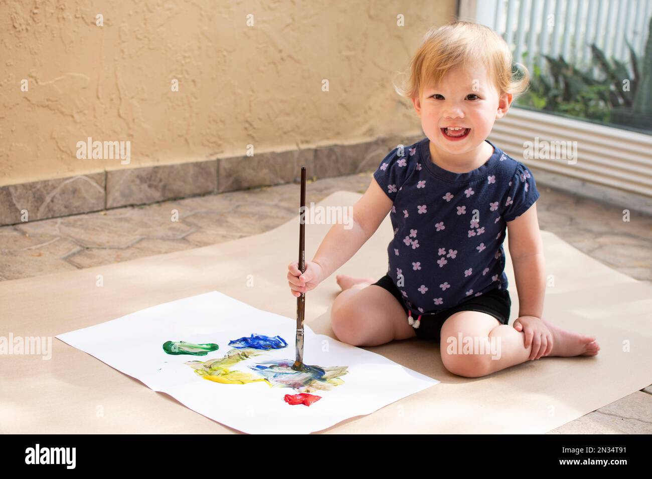 Happy cute caucasian toddler child painting with paints and a brush ...