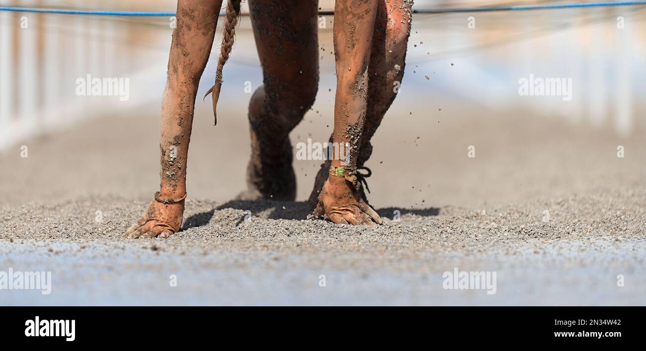 Mud race runners. Crawling, passing under a wire obstacles during ...