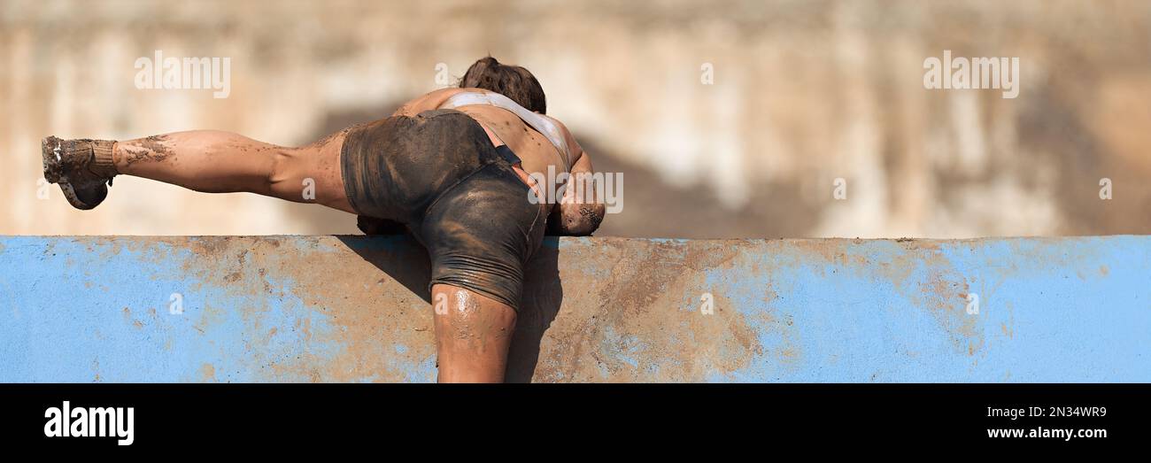 Mud race running. Running over obstacles female race participant ...