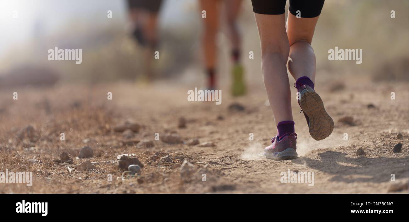 Group of young adults competition and running together through trails ...