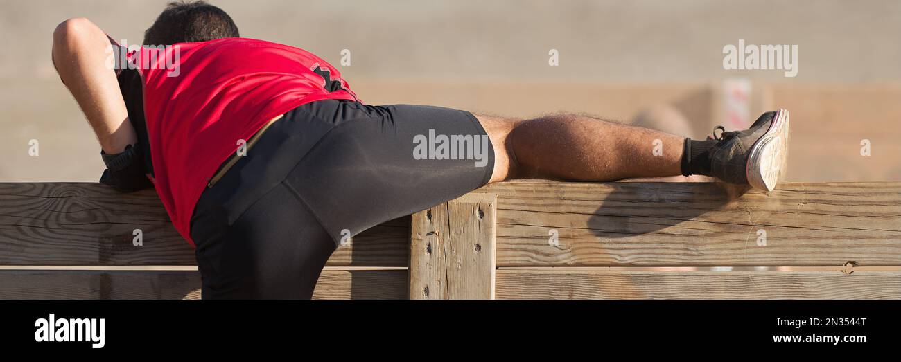 Participant in an obstacle course running and climbing a wall, jump ...