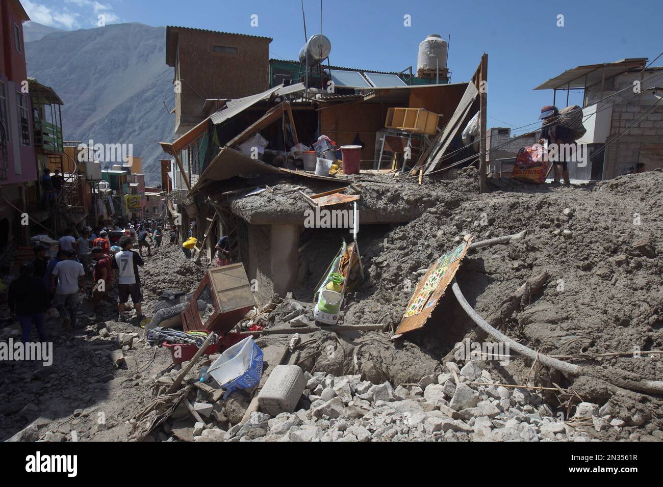 Residents walk on a street covered with debris caused by a landslide ...