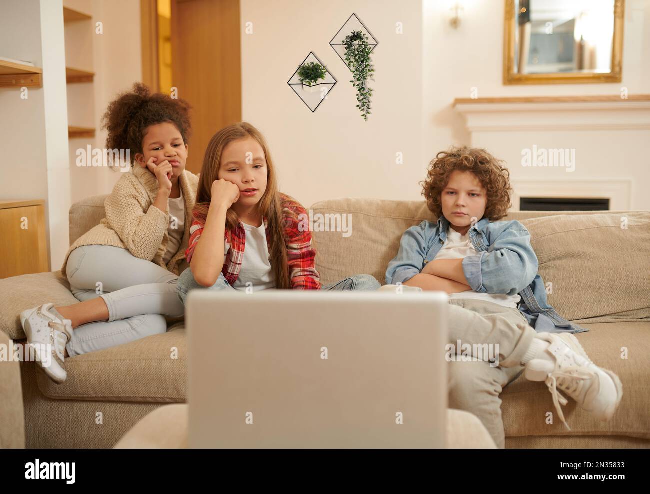 Three kids watching something on a laptop Stock Photo - Alamy