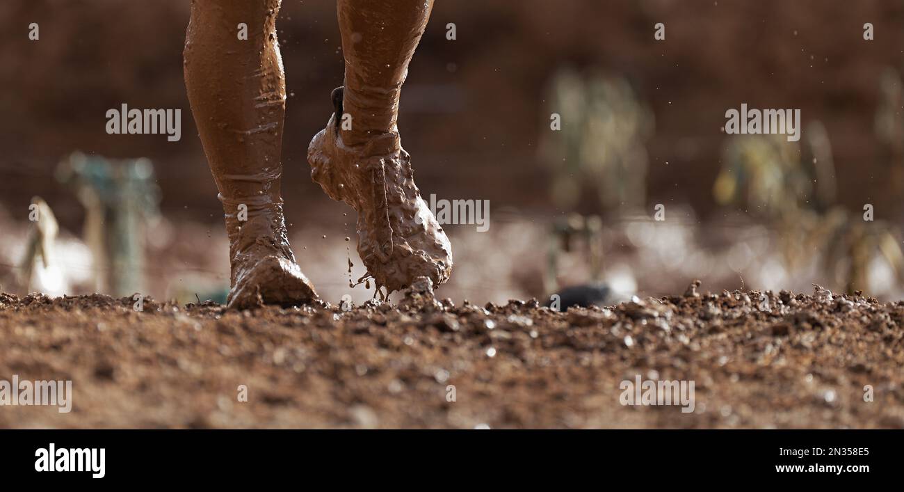 Mud race runner detail of the legs, muddy running shoes a run in the ...