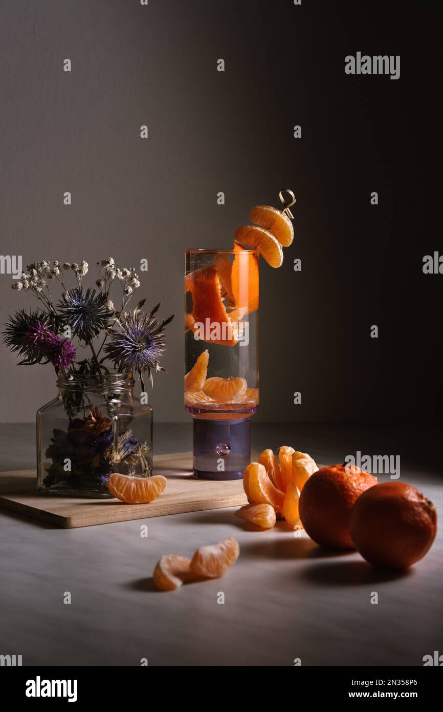 a purple glass of water and clementine skin in it, some fresh fruit ...