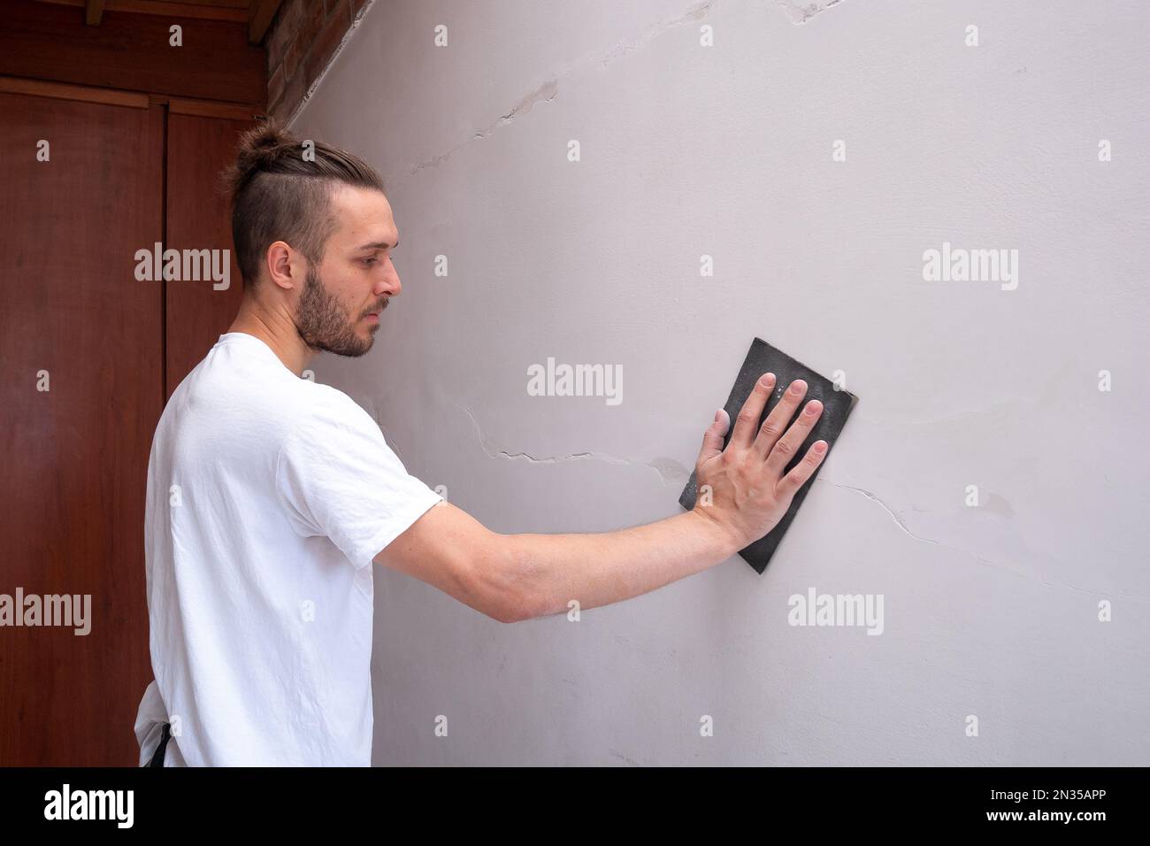 White Man Repairs White Wall Using Sandpaper Stock Photo - Alamy