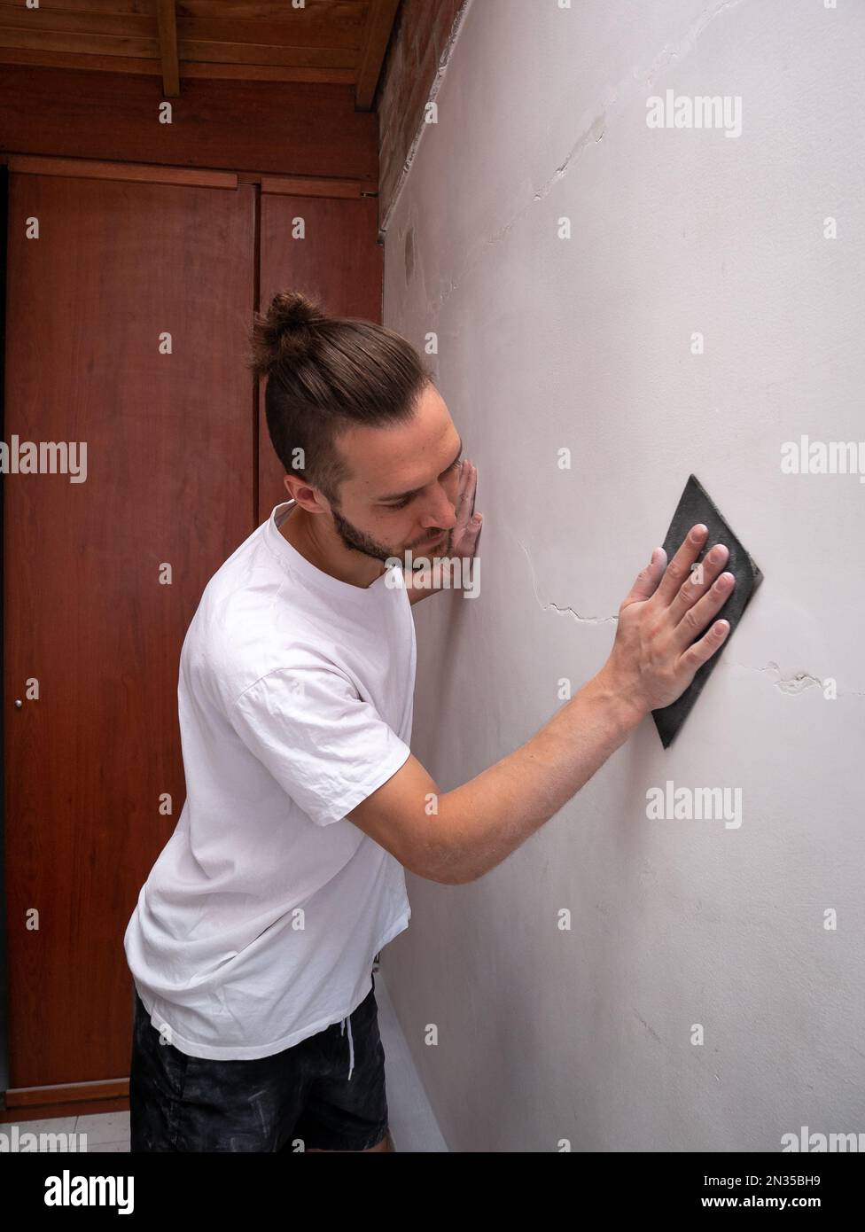 White Man Repairs White Wall Using Sandpaper Stock Photo - Alamy